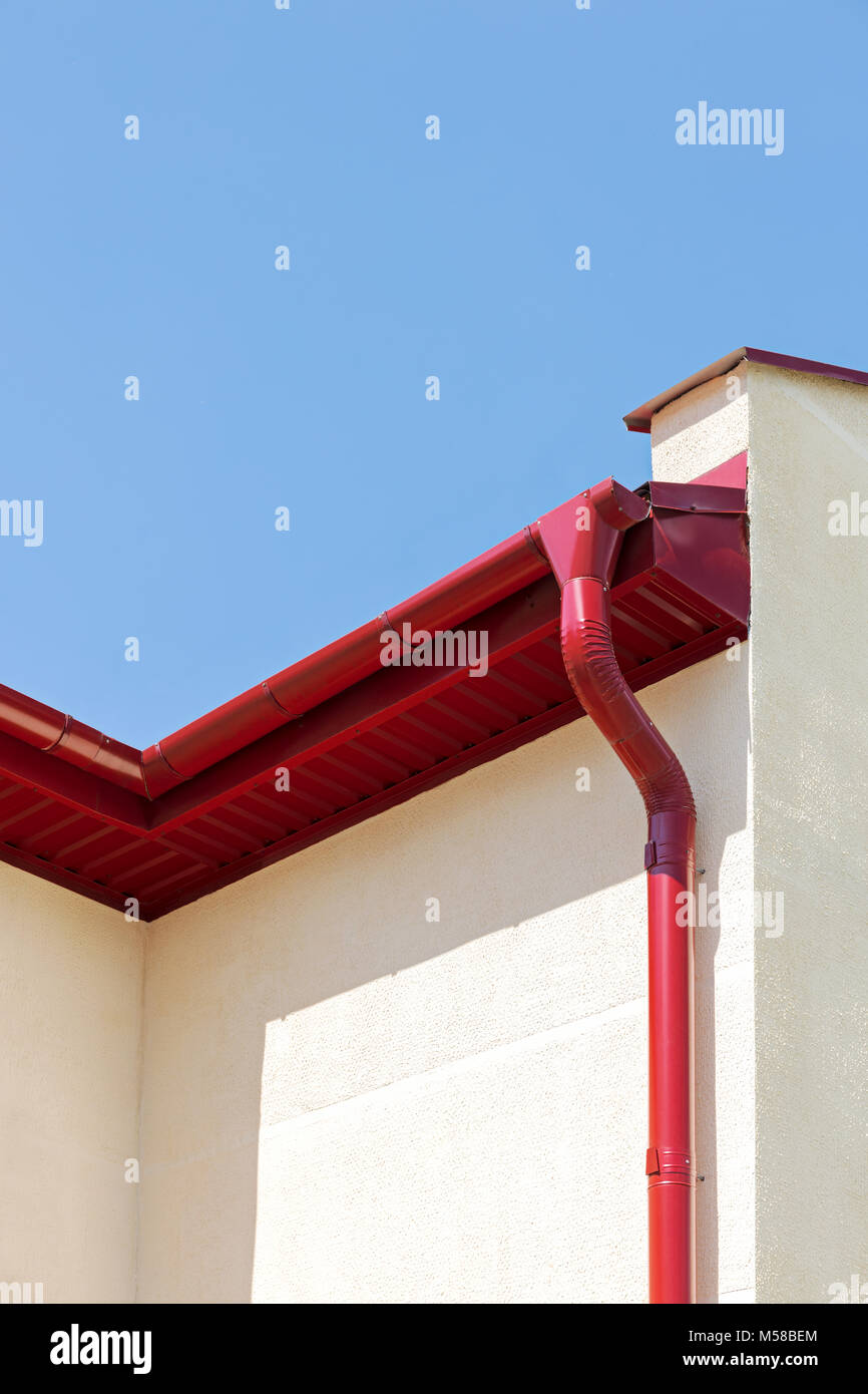 red metal drainpipe newly installed on plaster wall of building Stock ...