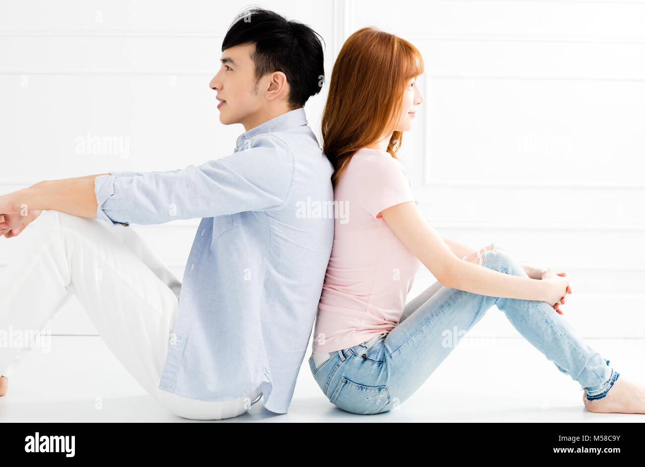 Young couple sitting together on the floor Stock Photo - Alamy
