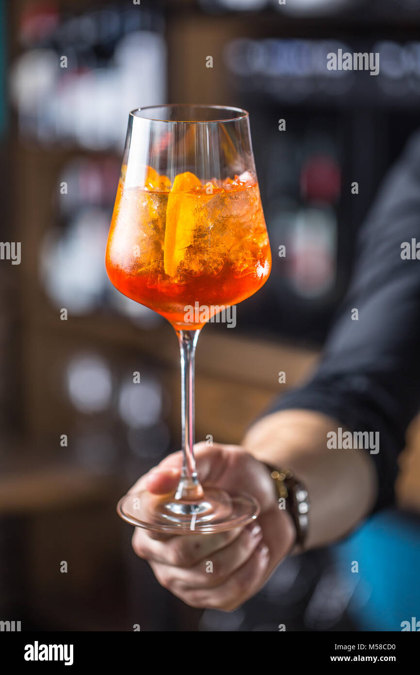 Aperol spritz drink. Bartender hand holding glass with Aperol Spritz ...