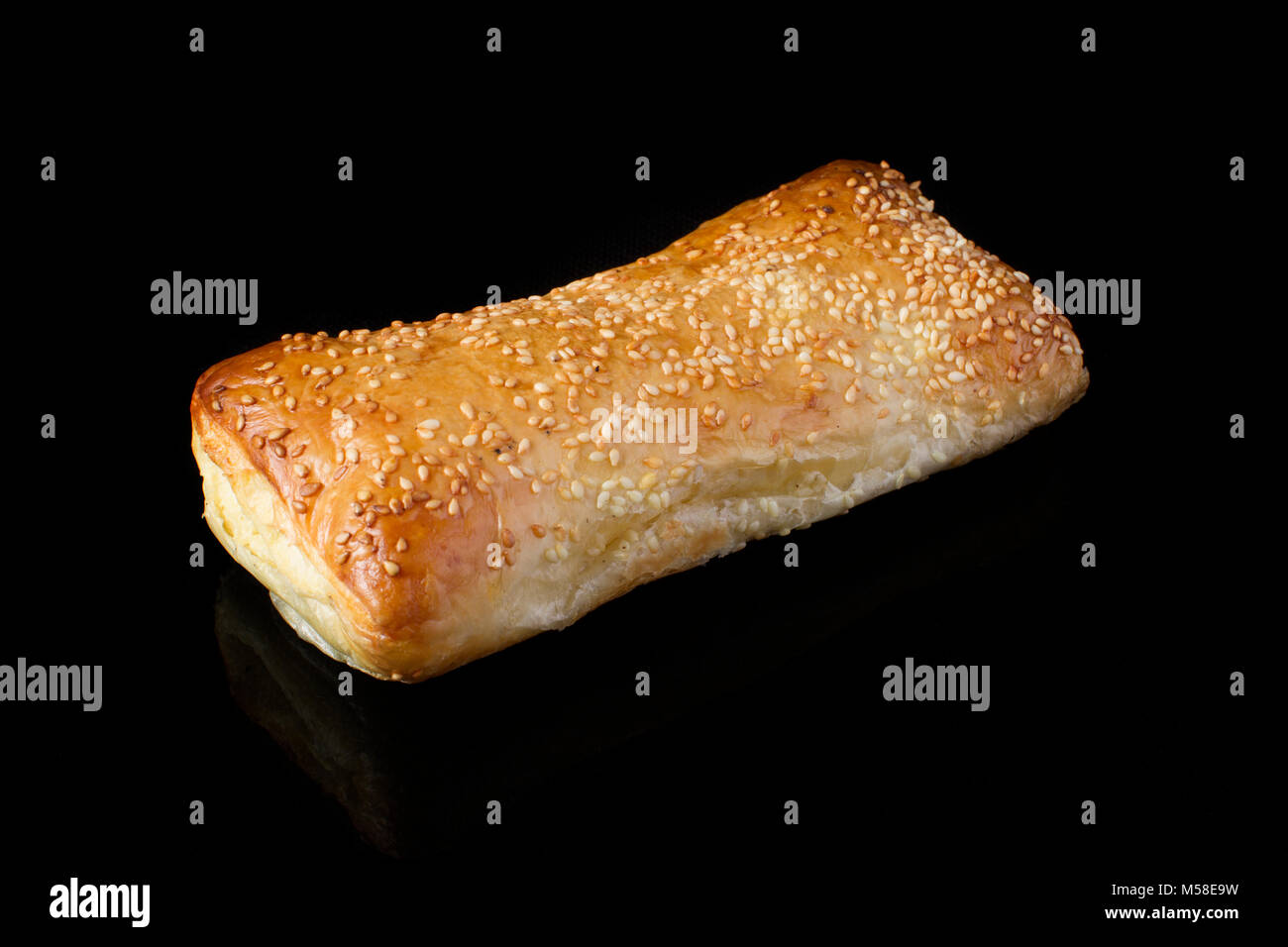 Puff pastry roll with sesame seeds on a black background Stock Photo ...