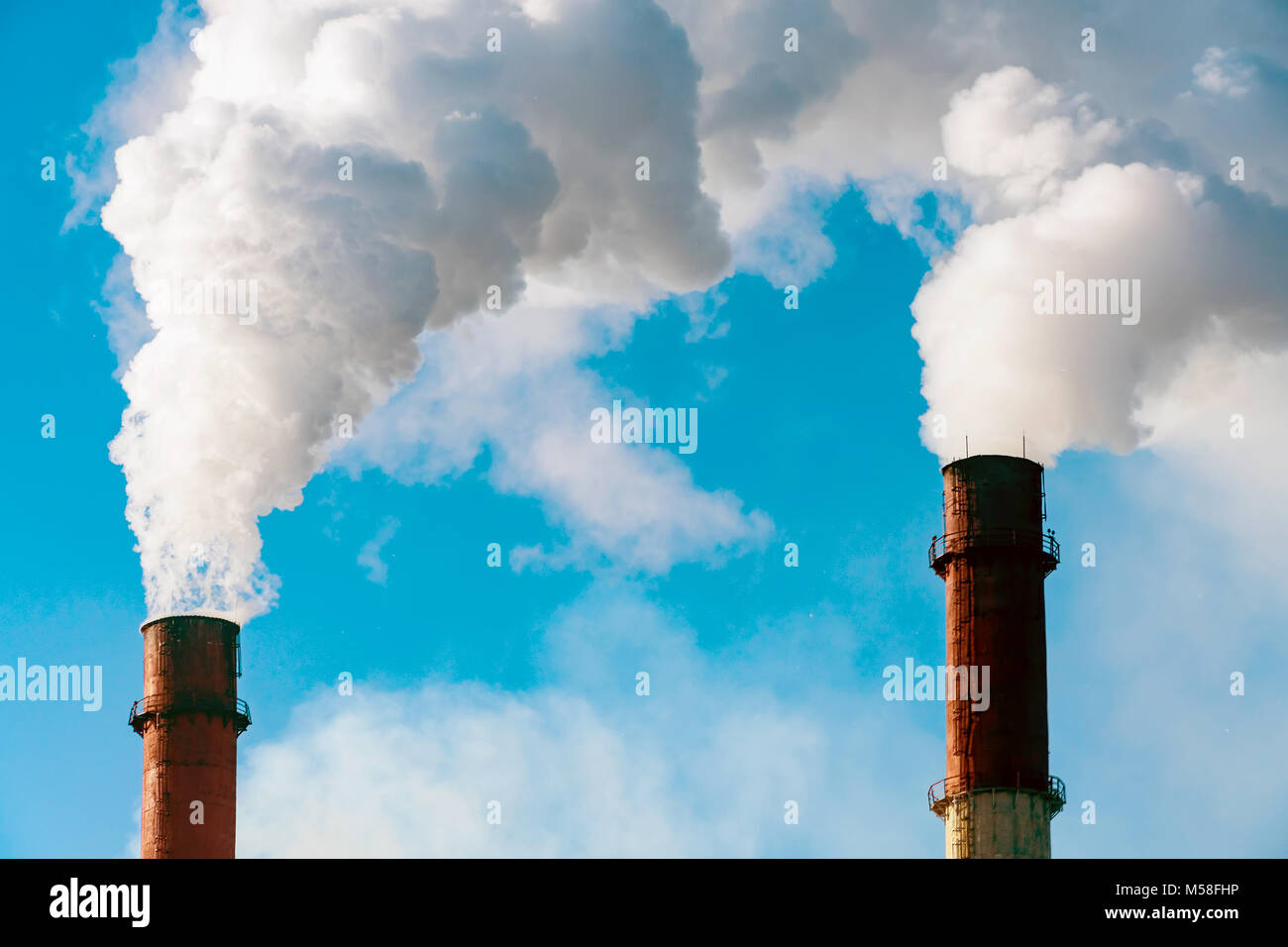 Thick smoke from factory chimneys on a blue sky background Stock Photo ...
