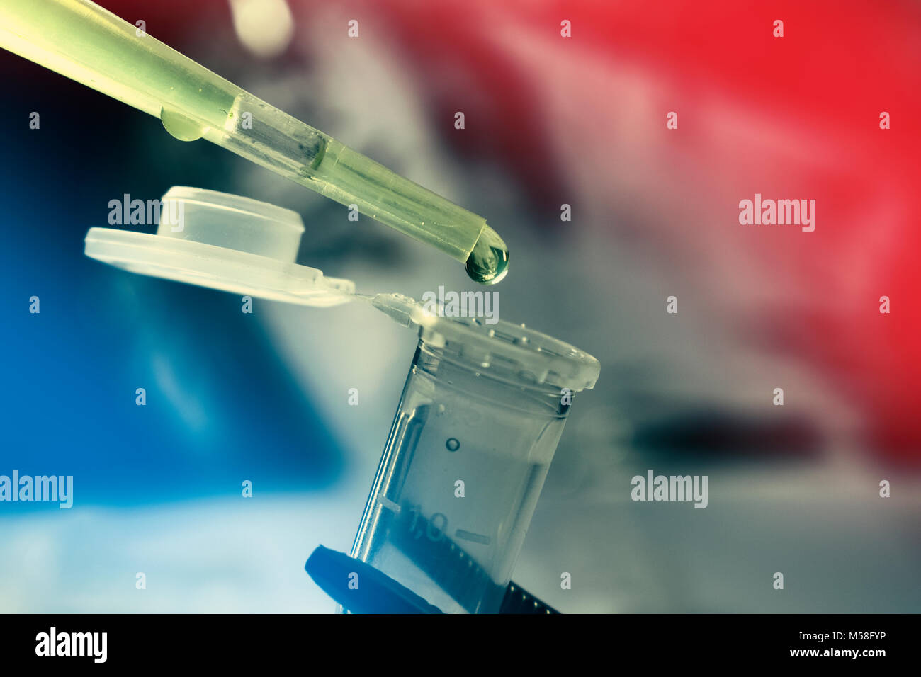 Pipette drop of stem cells research fluid in a vial held by forceps ...