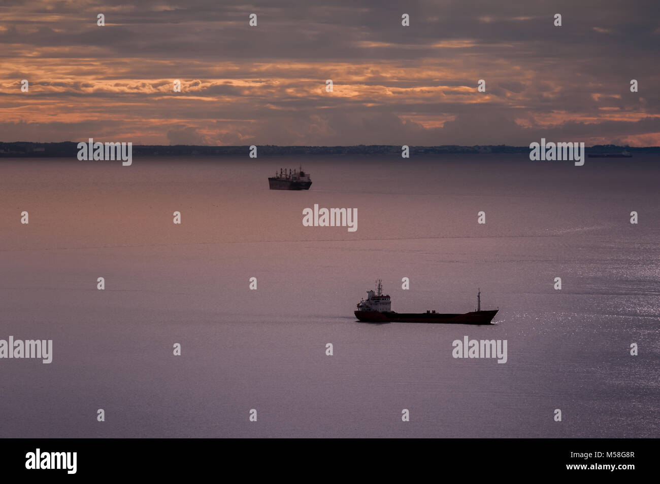 Seascape with ships at sunset with cloudy sky Stock Photo - Alamy