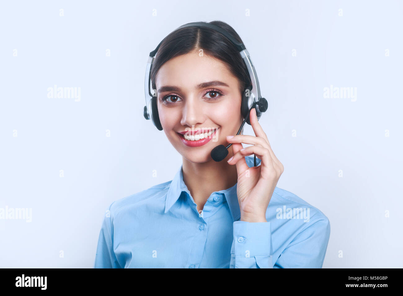 smiling customer support female phone operator in headset, against grey background. Consulting ...