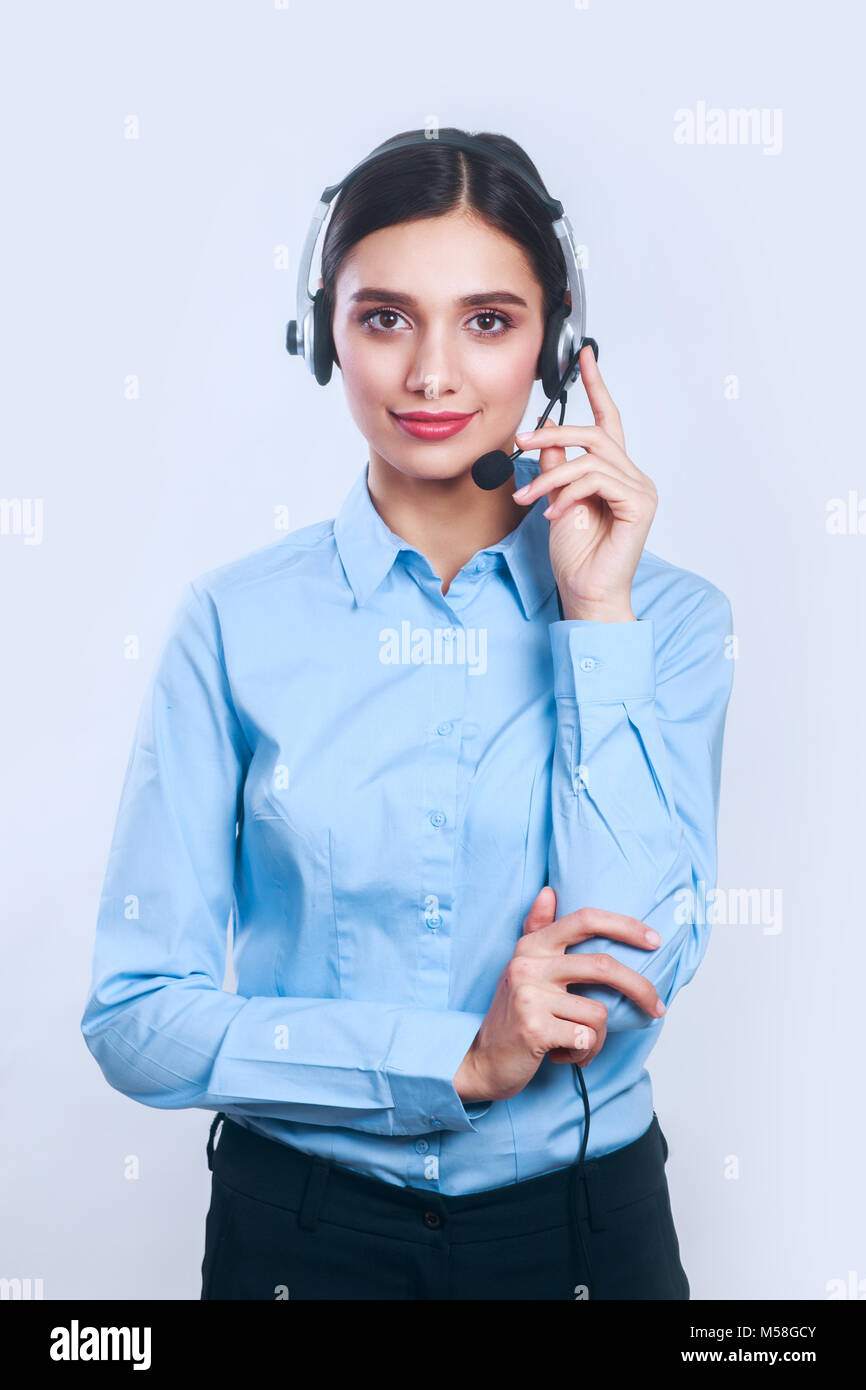 smiling customer support female phone operator in headset, against grey background. Consulting ...