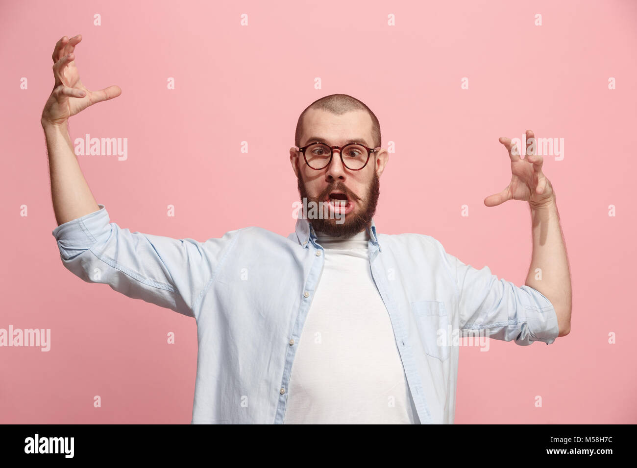 Portrait of an angry man looking at camera isolated on a pink ...