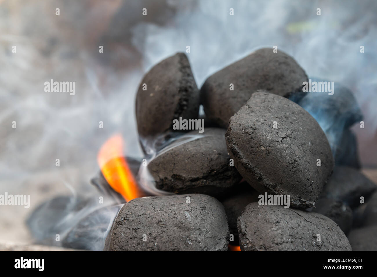 Fire up the grill with briquettes with a lot of smoke Stock Photo - Alamy