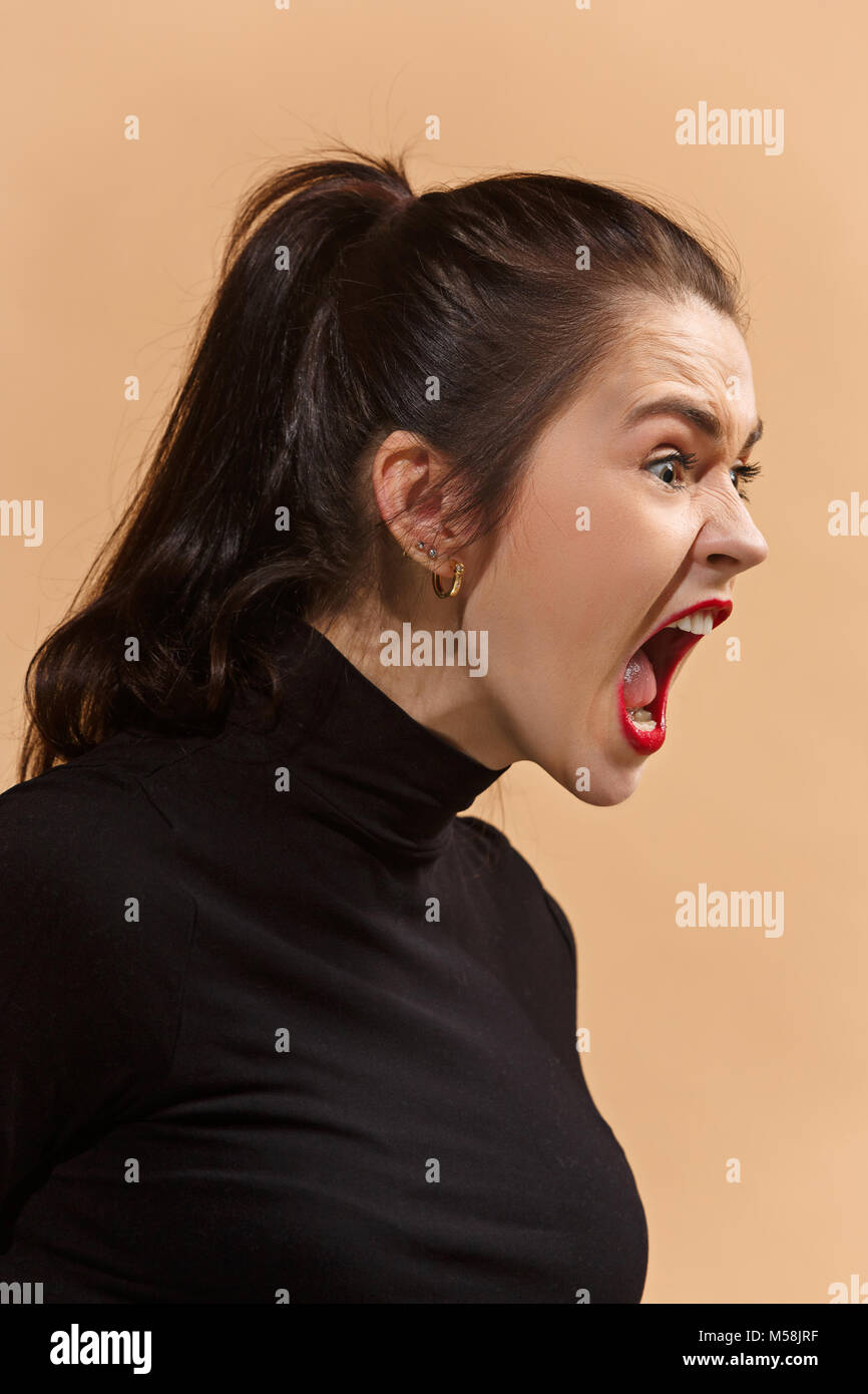 The young emotional angry woman screaming on pastel studio background ...