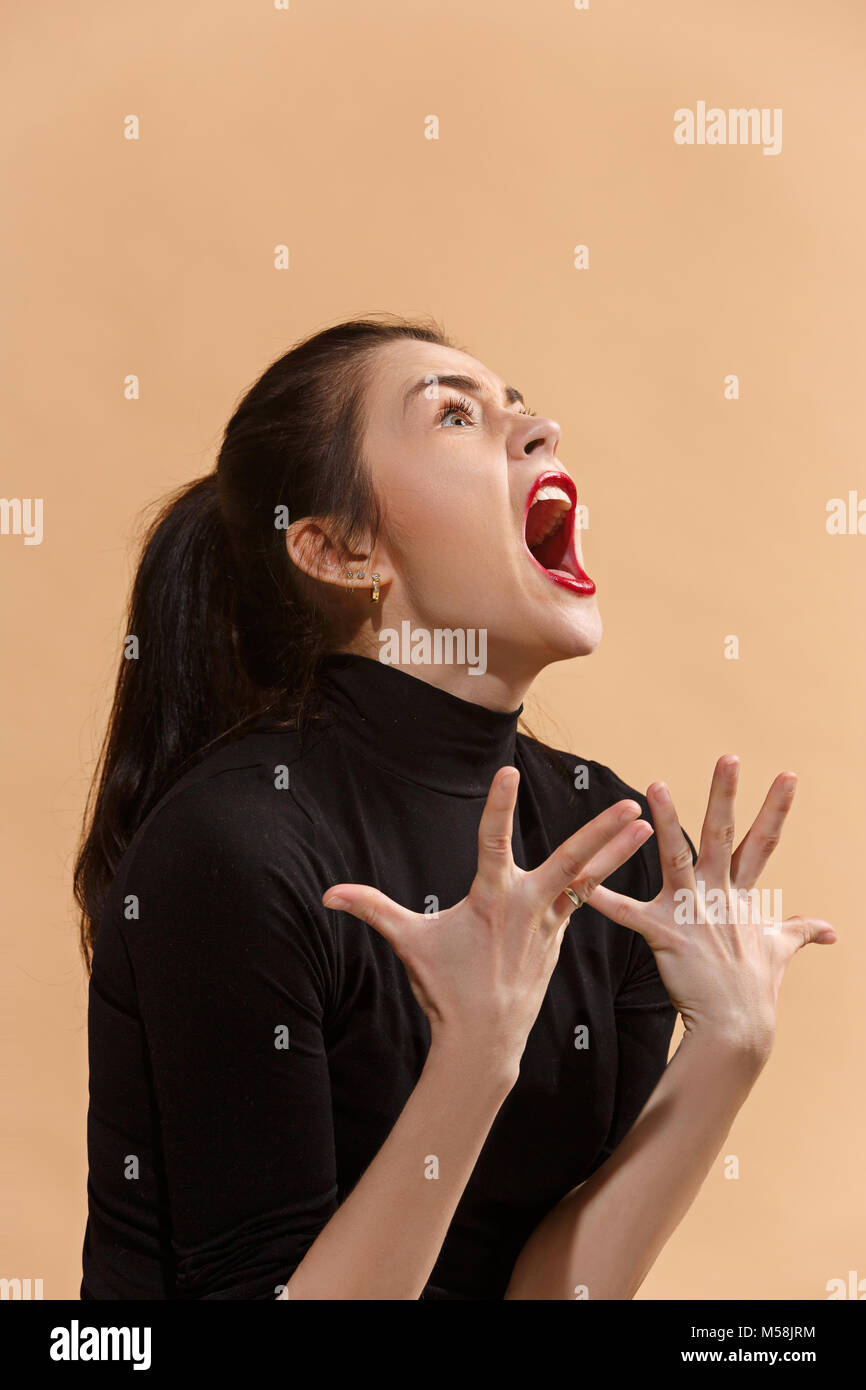 The young emotional angry woman screaming on pastel studio background ...
