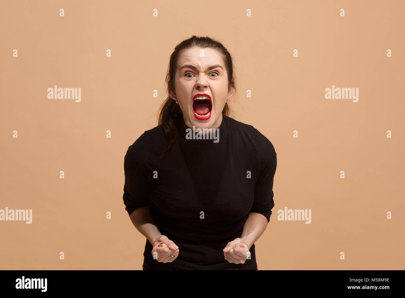 The young emotional angry woman screaming on pastel studio background ...
