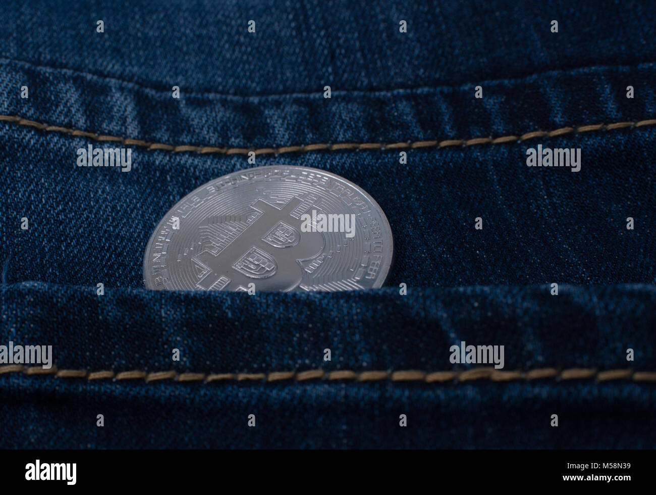 Bitcoin gold coin in the pocket of blue jeans Stock Photo - Alamy