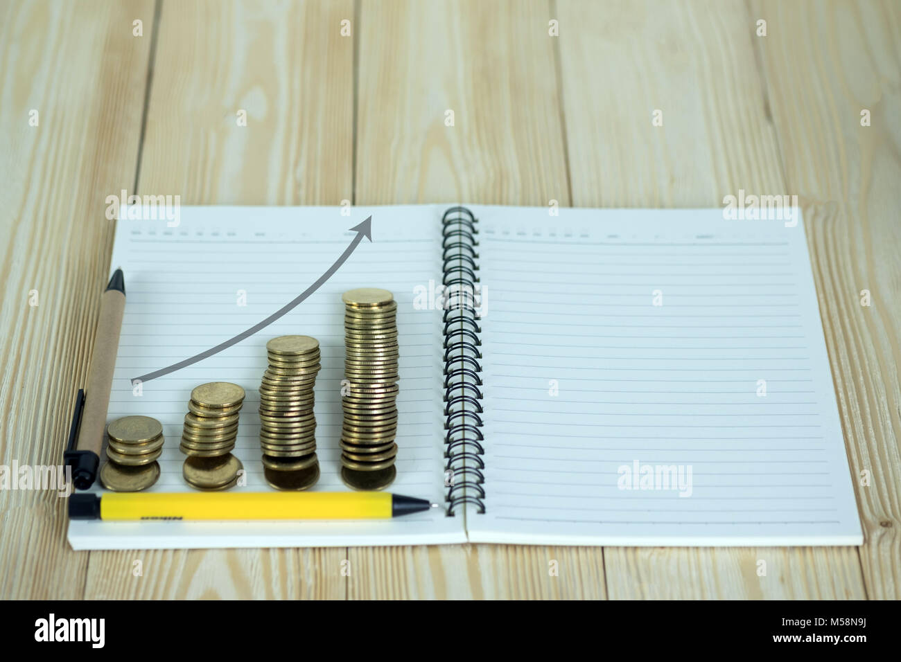 Steps of coins stack with notebook paper on wooden working table with ...