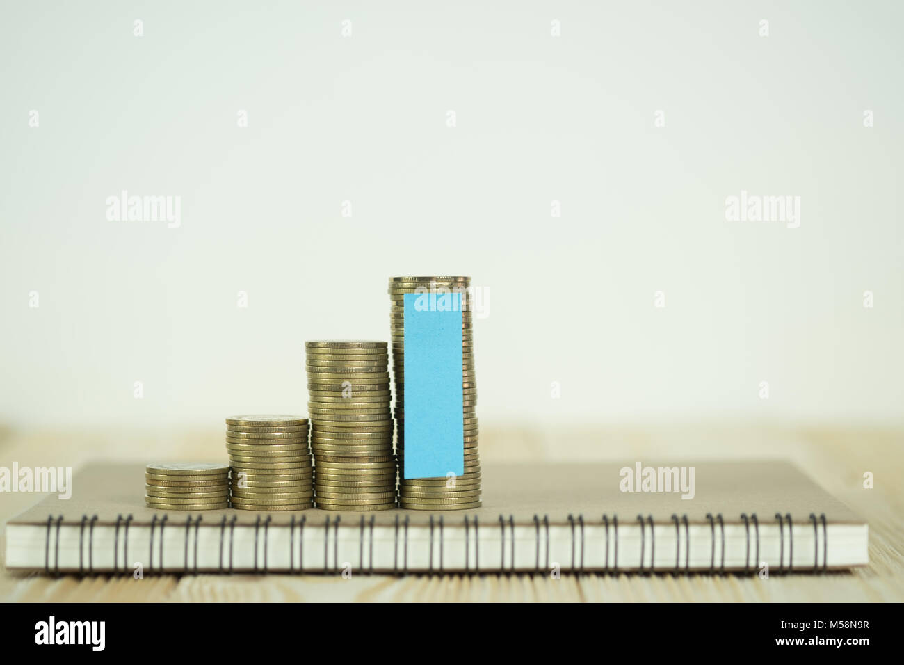 Steps of coins stack with notebook paper on wooden working table with ...