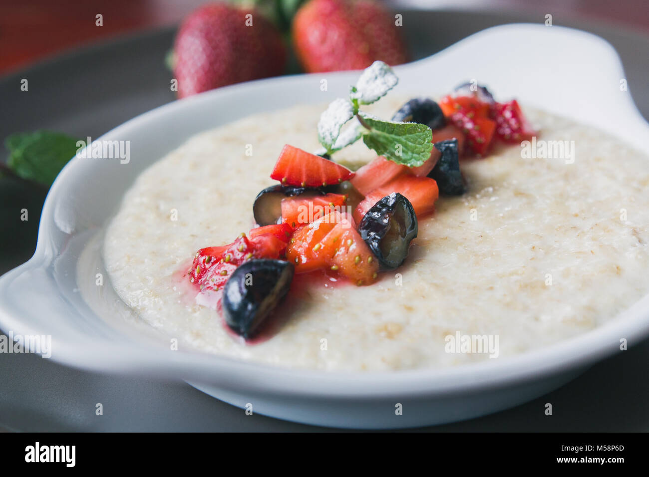 Bowl of oatmeal porridge with fruits and greens, hot and healthy food ...
