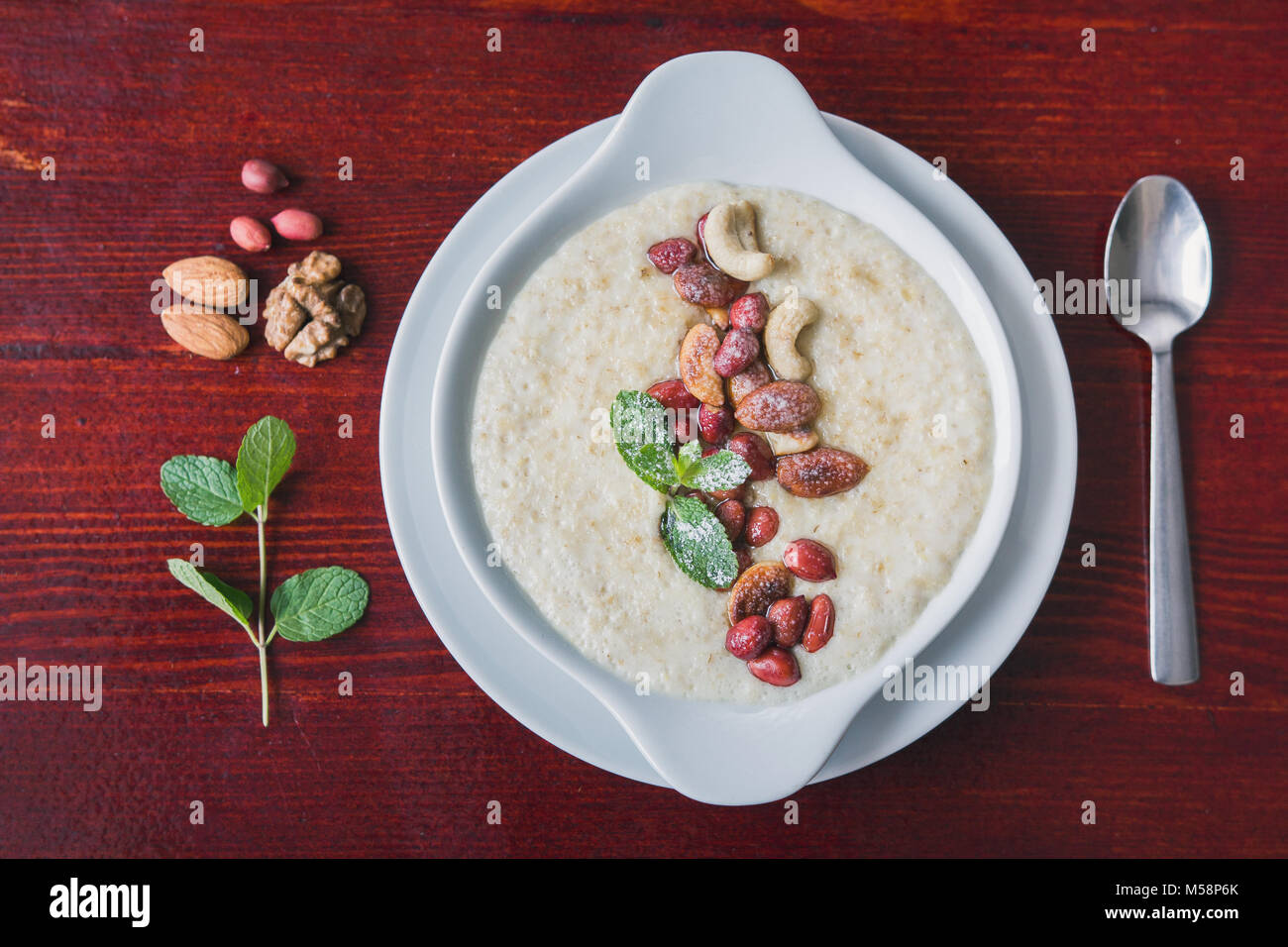 Bowl of oatmeal porridge with nuts and greens, hot and healthy food for ...
