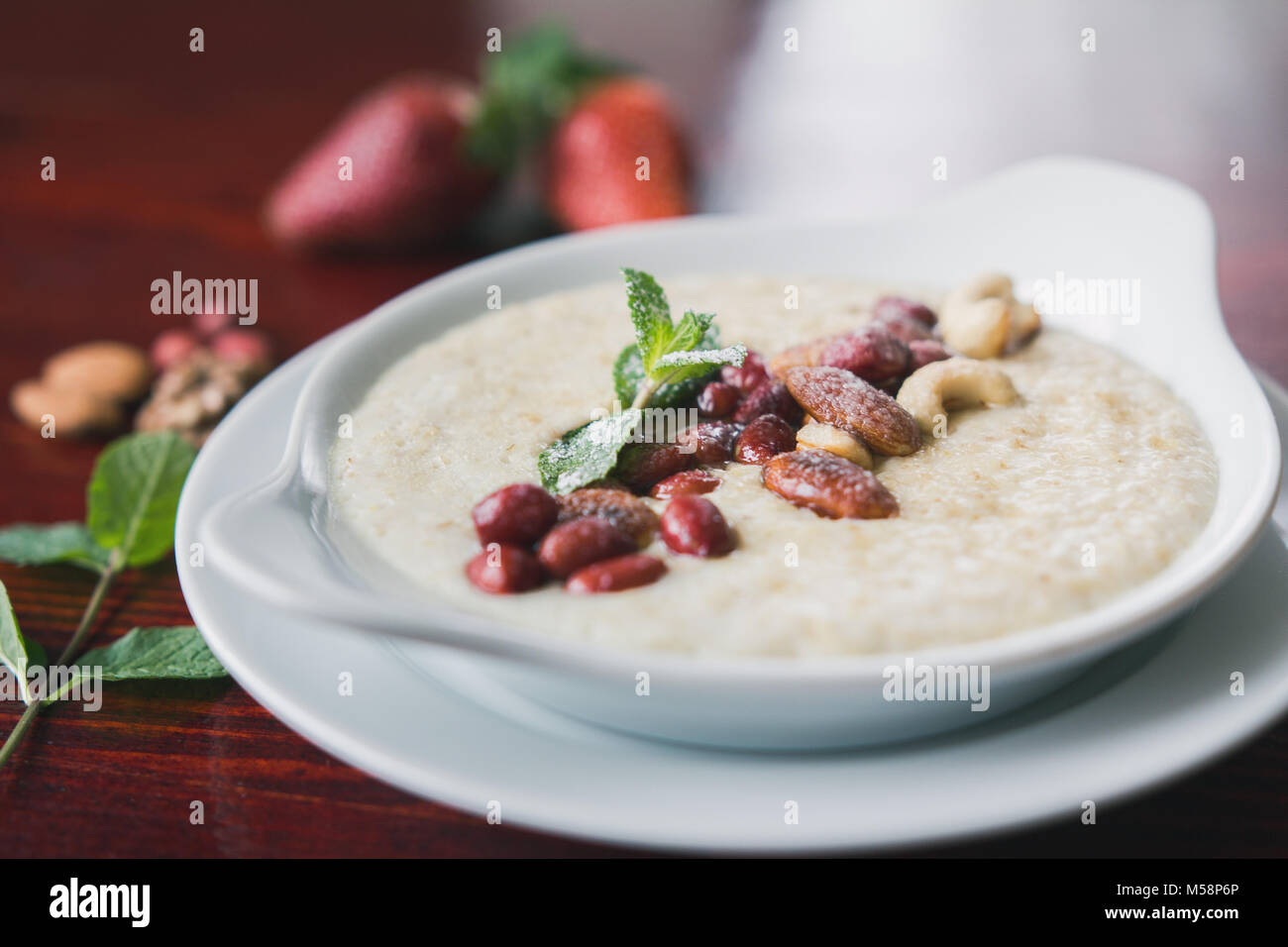 Bowl of oatmeal porridge with nuts and greens, hot and healthy food for ...