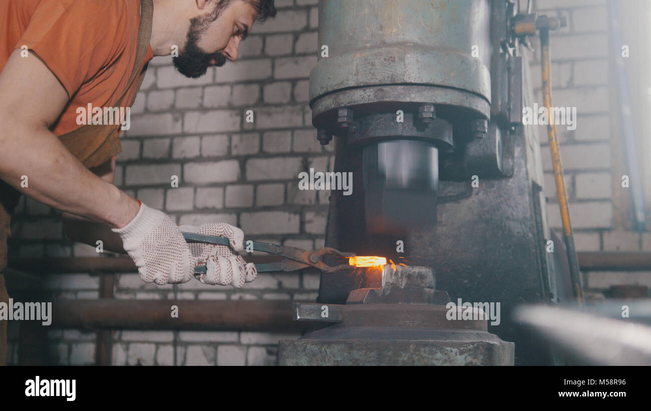 Man blacksmith forges the metal at the mechanical hammer Stock Photo ...