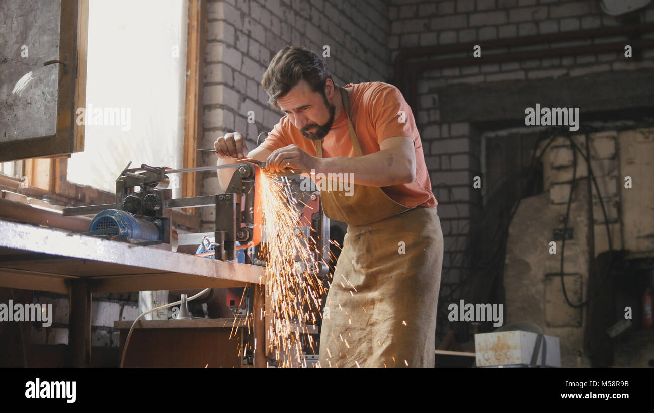 Grinding metal tools with sparkles - forge workshop Stock Photo - Alamy