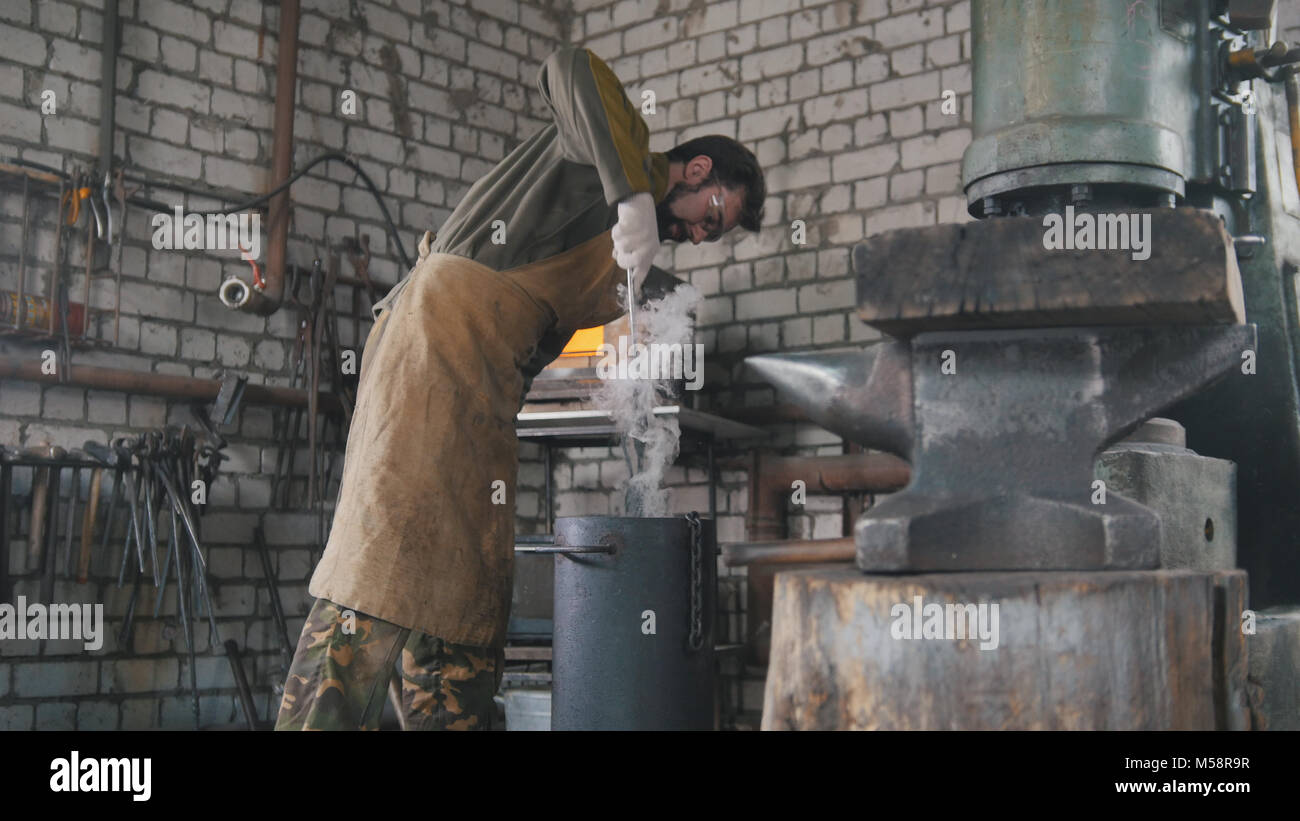 Blacksmith manually temper steel knife in engine oil Stock Photo - Alamy