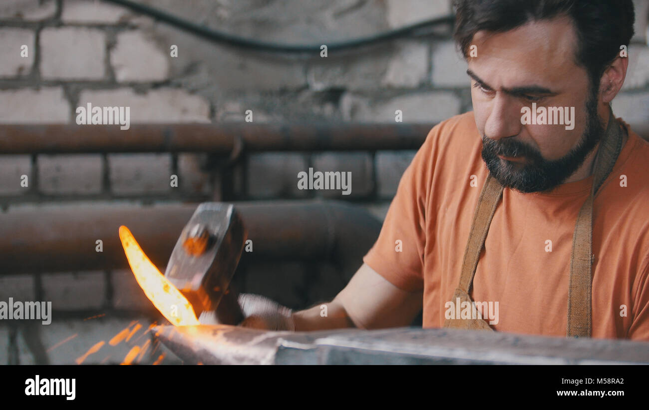 Muscular blacksmith in forge hammering steel products Stock Photo - Alamy