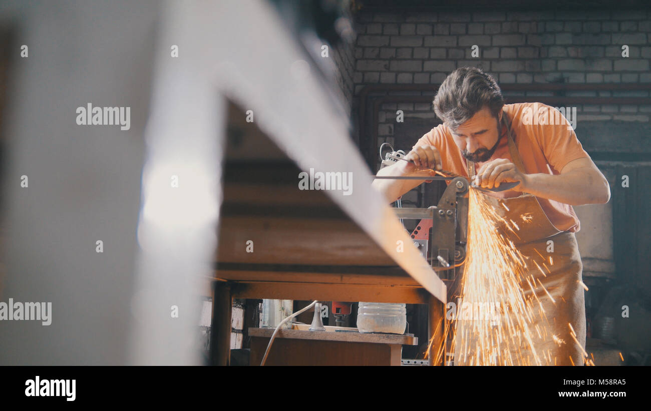 Grinding metal tools with sparkles - forge workshop Stock Photo - Alamy