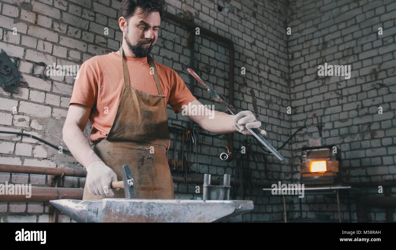 Muscular man blacksmith with hammer in forge creating steel knife Stock ...