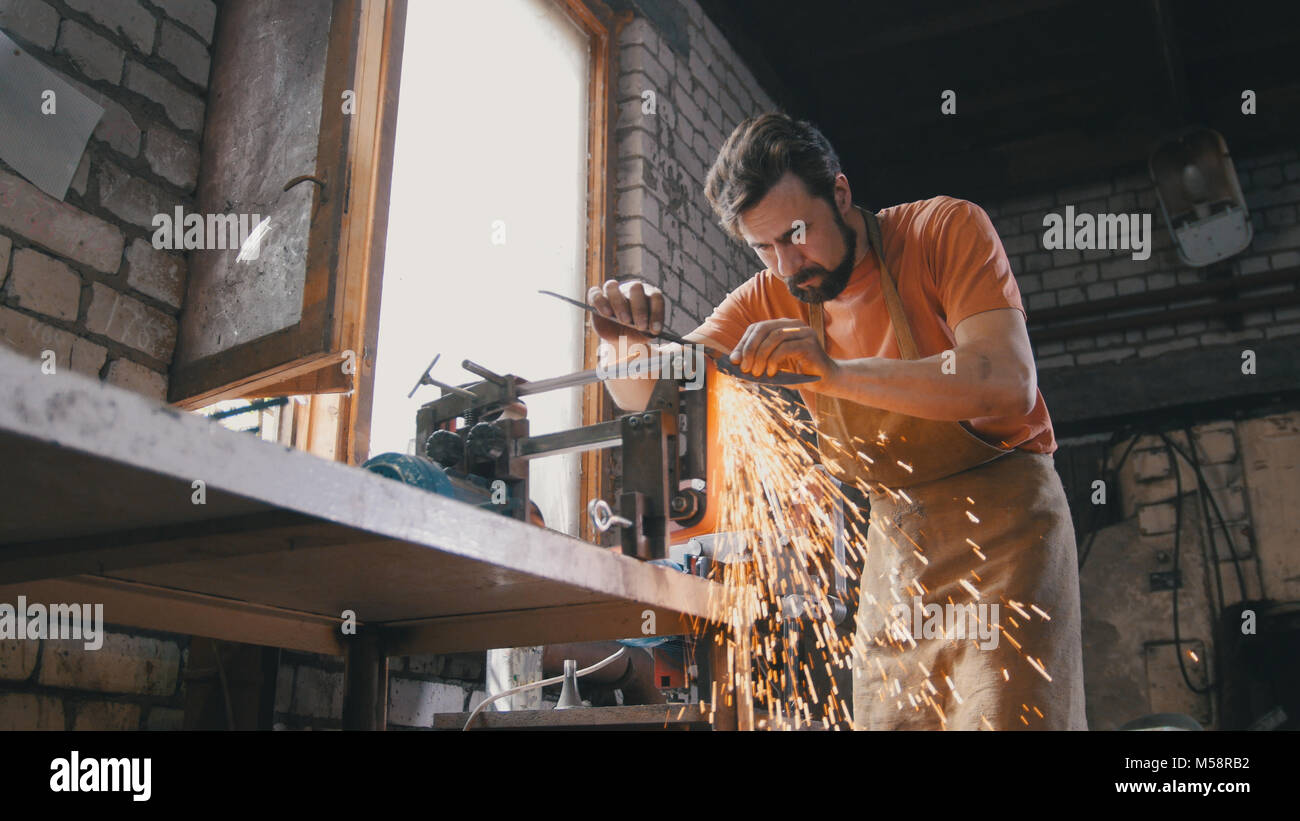 Grinding metal tools with sparkles - forge workshop Stock Photo - Alamy