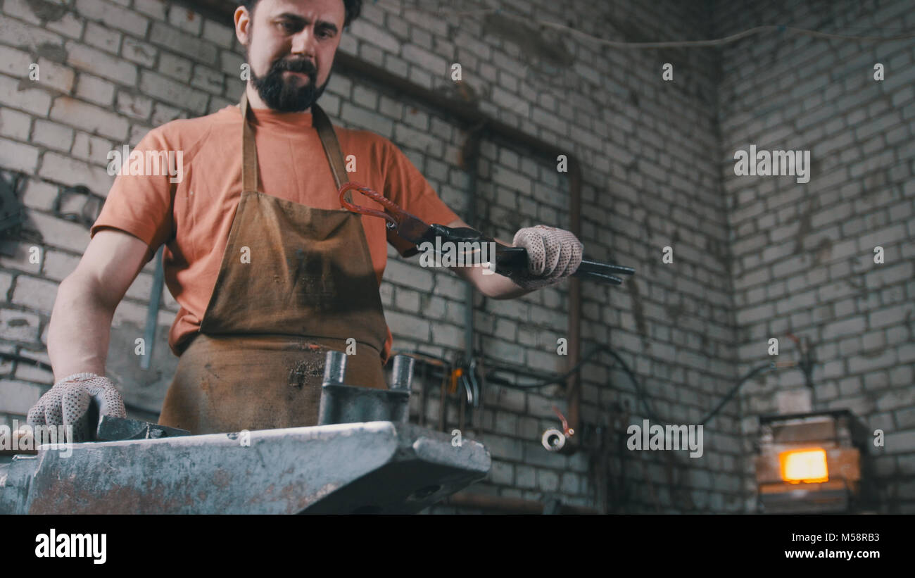 Muscular blacksmith in forge hammering steel products Stock Photo - Alamy