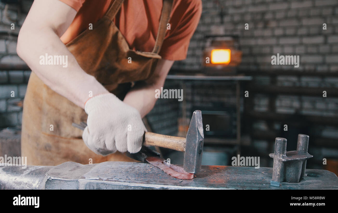 The smith gives shape with a hammer to a red-hot metal object Stock ...