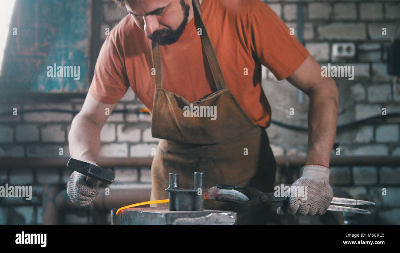 The smith gives shape with a hammer to a red-hot metal object Stock ...