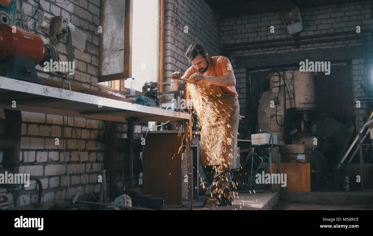 Grinding metal tools with sparkles - forge workshop Stock Photo - Alamy