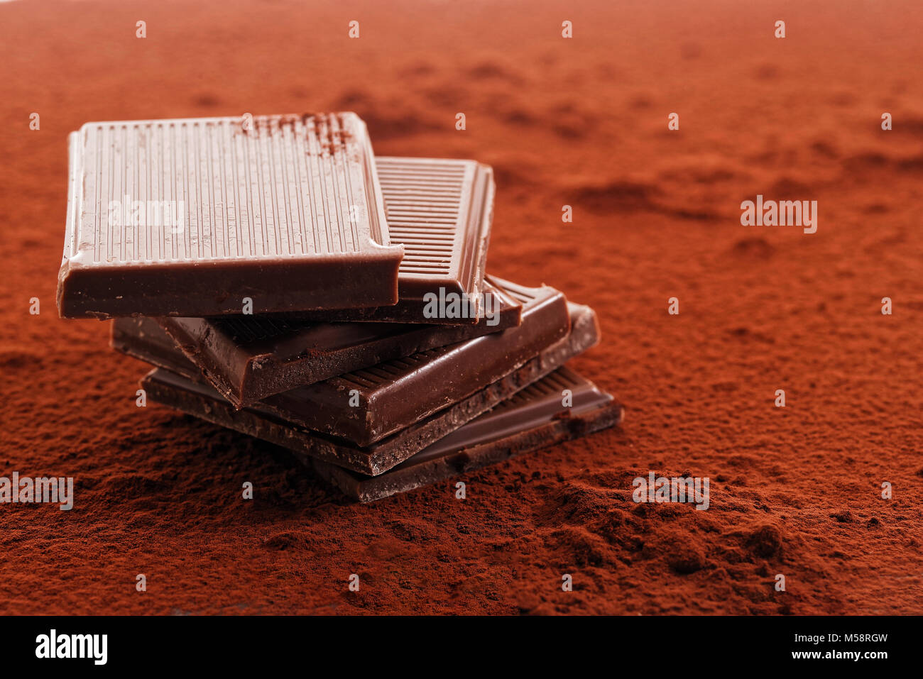 Broken dark chocolate, cocoa powder and coffee beans on a wooden table ...