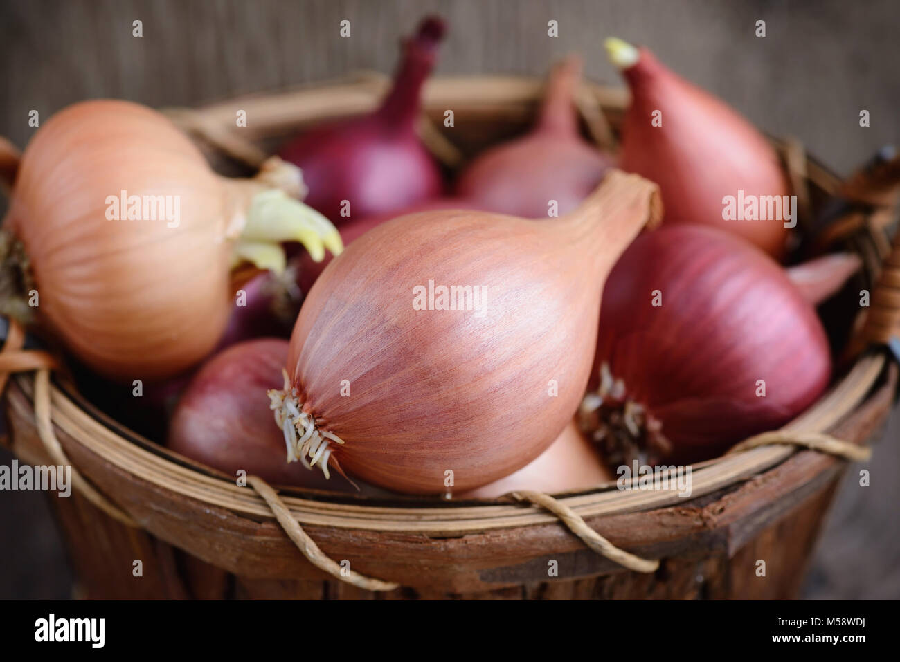 Dry bulb onions in a basket on wooden background Stock Photo - Alamy