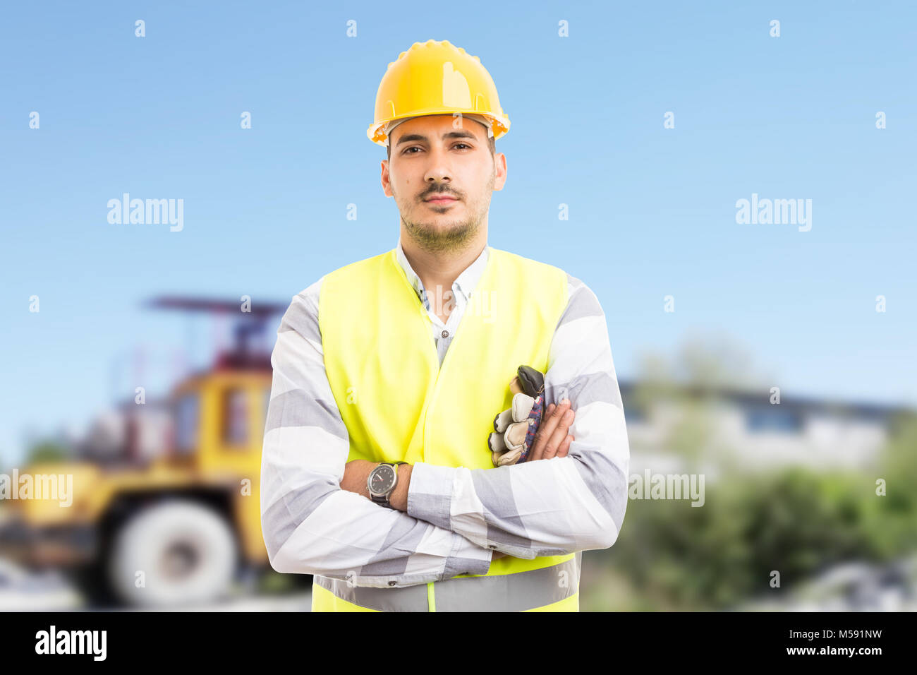 Confident worker standing with arms crossed on a pit or construction ...