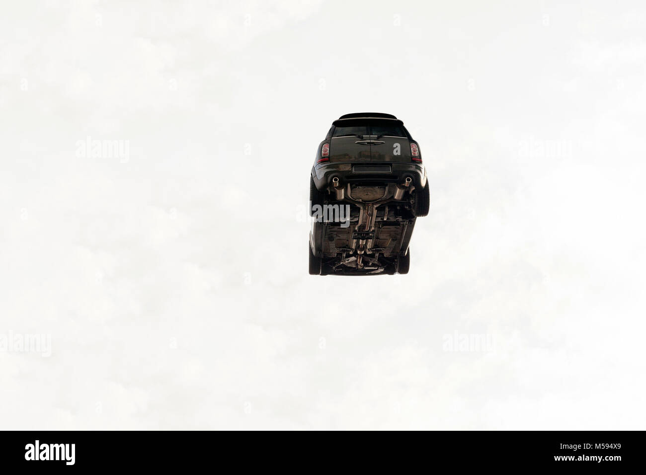 A car flying through the air (in the pale blue sky) with the underside ...