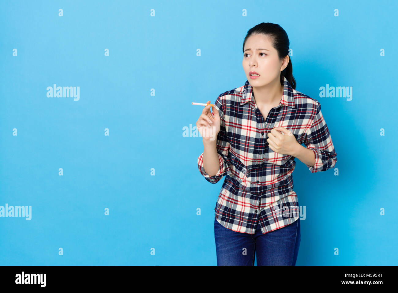 elegant beauty woman standing in blue background smoking and getting ...