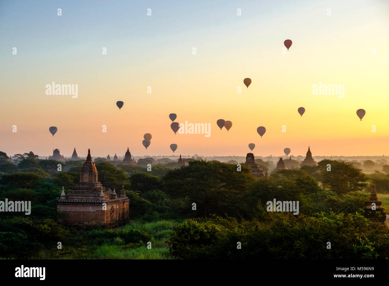 Hot-air balloons flying over the pagodas of Bagan and the foggy plains ...