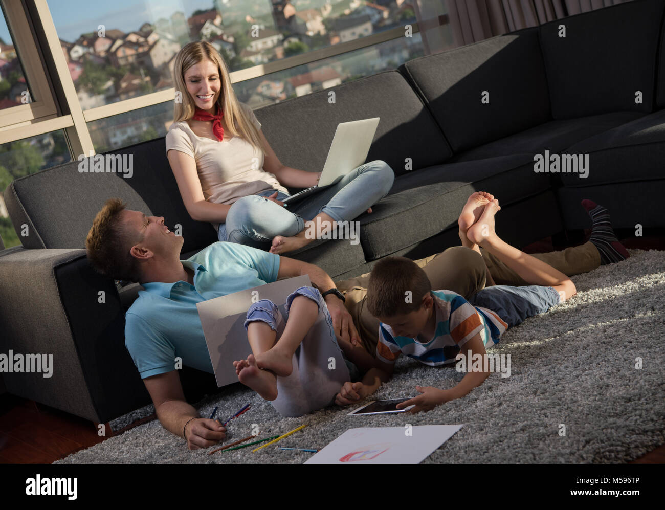 Happy Young Family Playing Together at home on the floor using a laptop ...