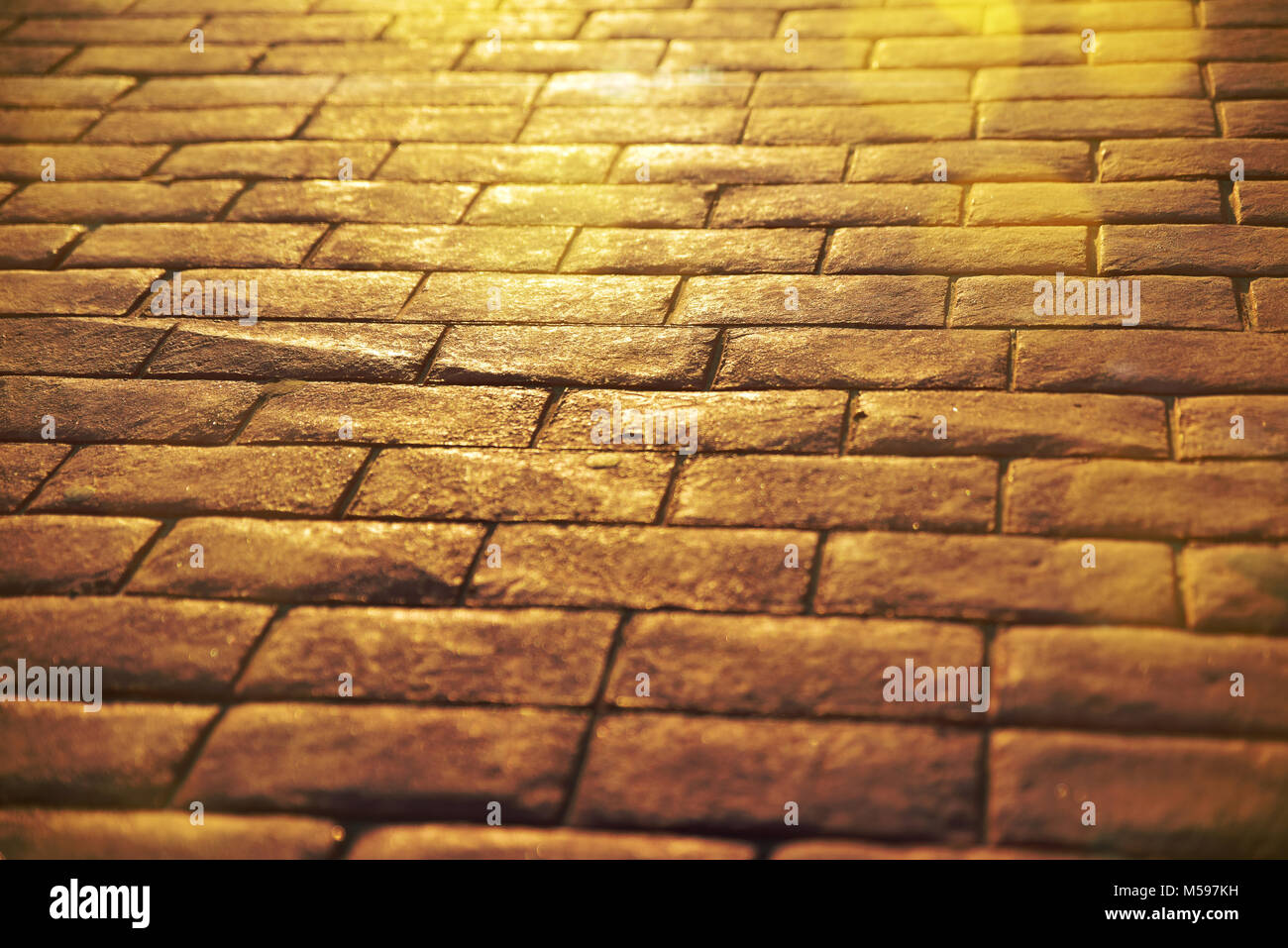 Road background of stone slabs with sun reflection and golden glitters ...