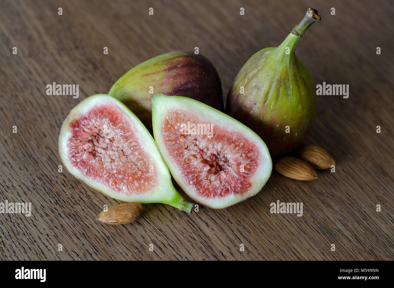 Close-up of fresh figs with one slised ripe fig and three almond nuts ...