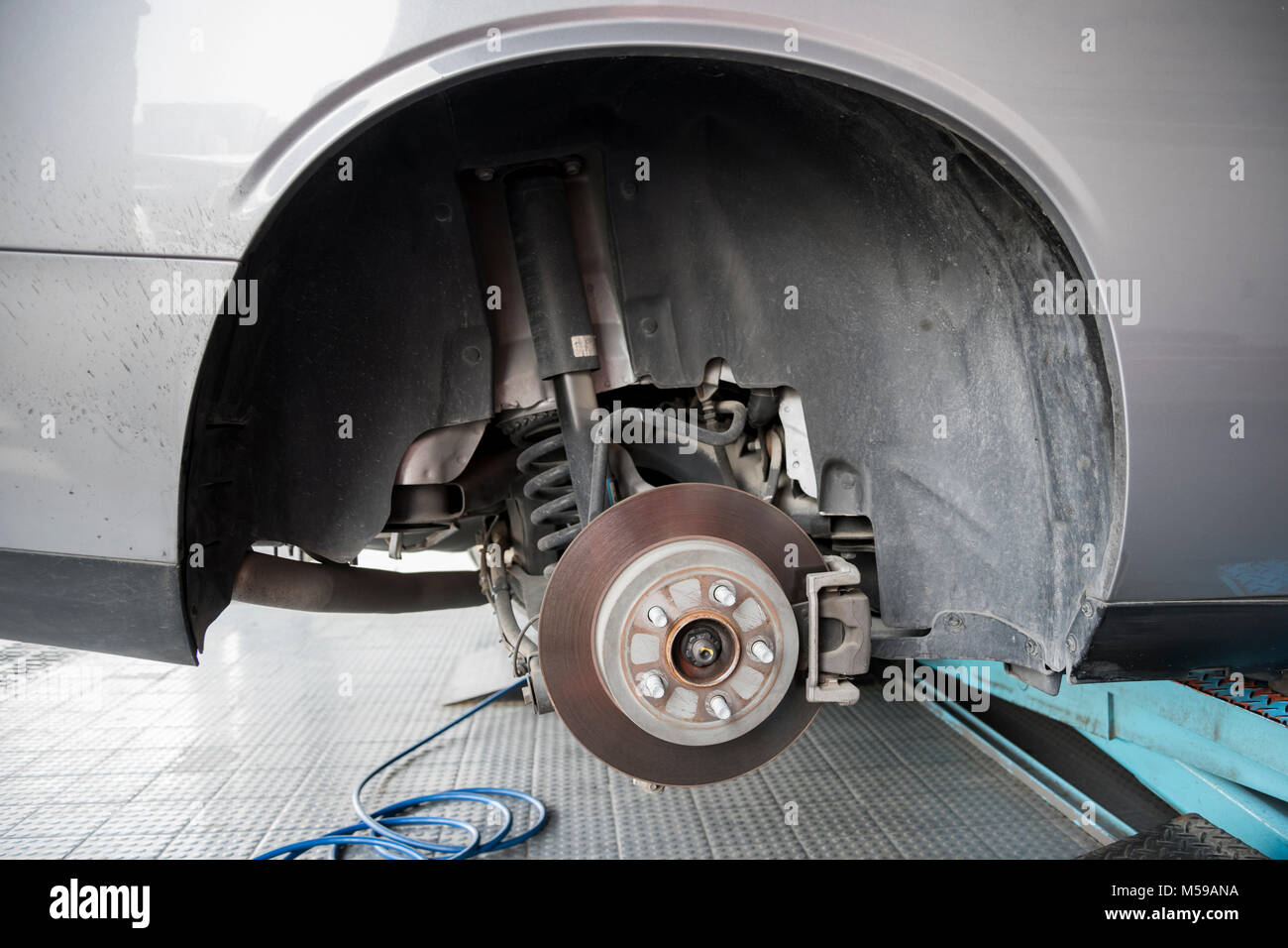 exposed disc brake system while changing a tire in car garage ...