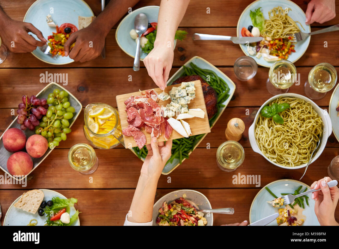 group of people eating at table with food Stock Photo - Alamy