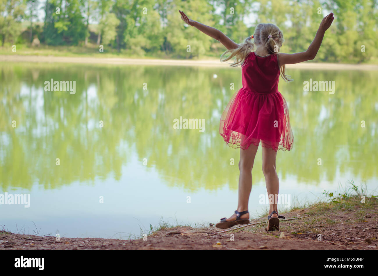 adorable blond girl jumping in the strand of the lake Stock Photo - Alamy