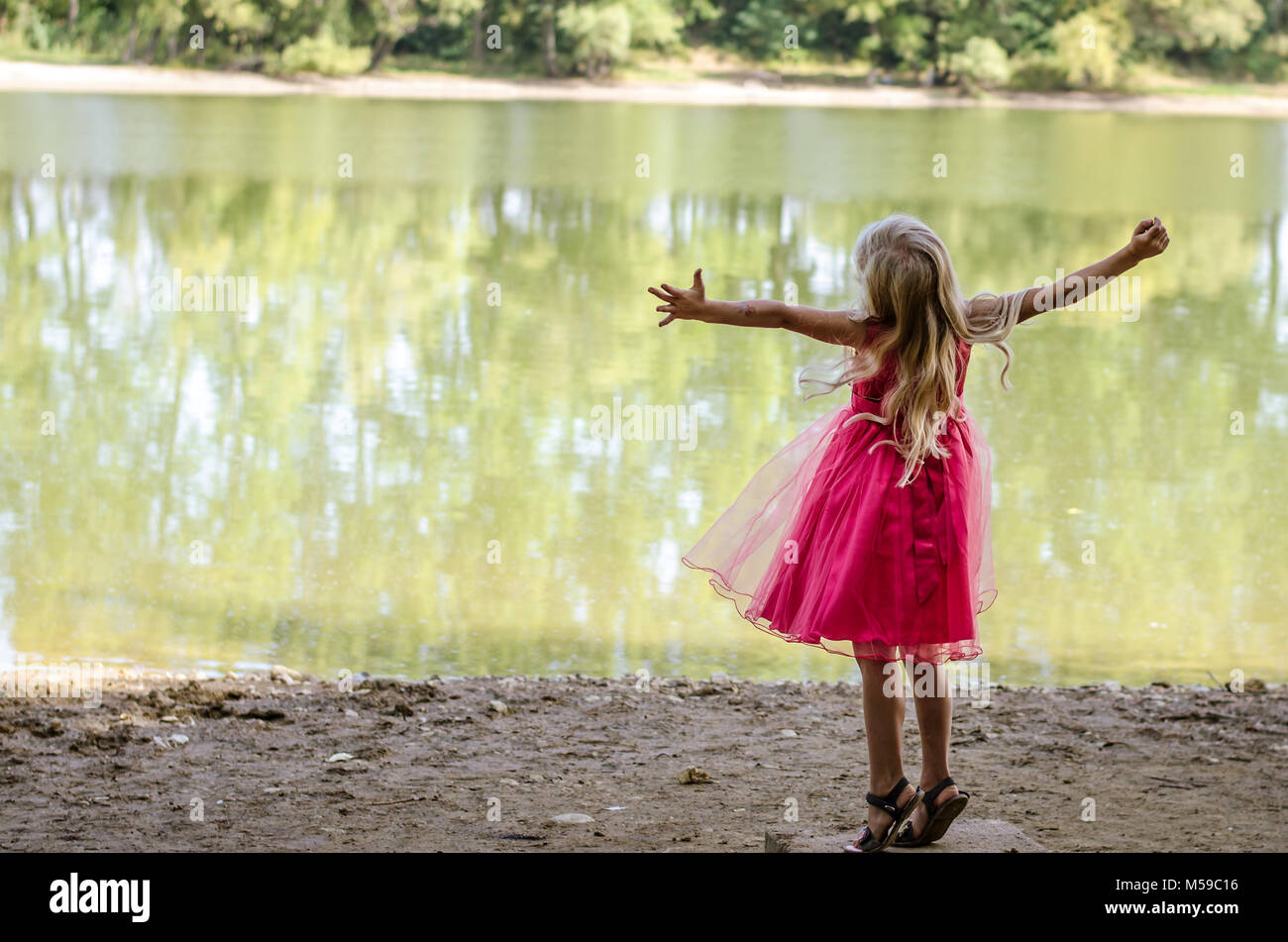 adorable blond girl jumping in the strand of the lake Stock Photo - Alamy