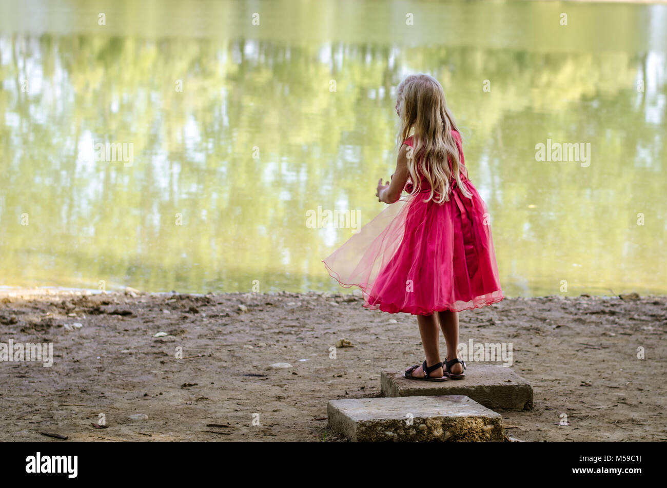 adorable blond girl jumping in the strand of the lake Stock Photo - Alamy