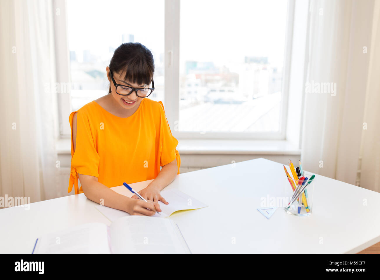 happy student girl with book and notebook at home Stock Photo - Alamy