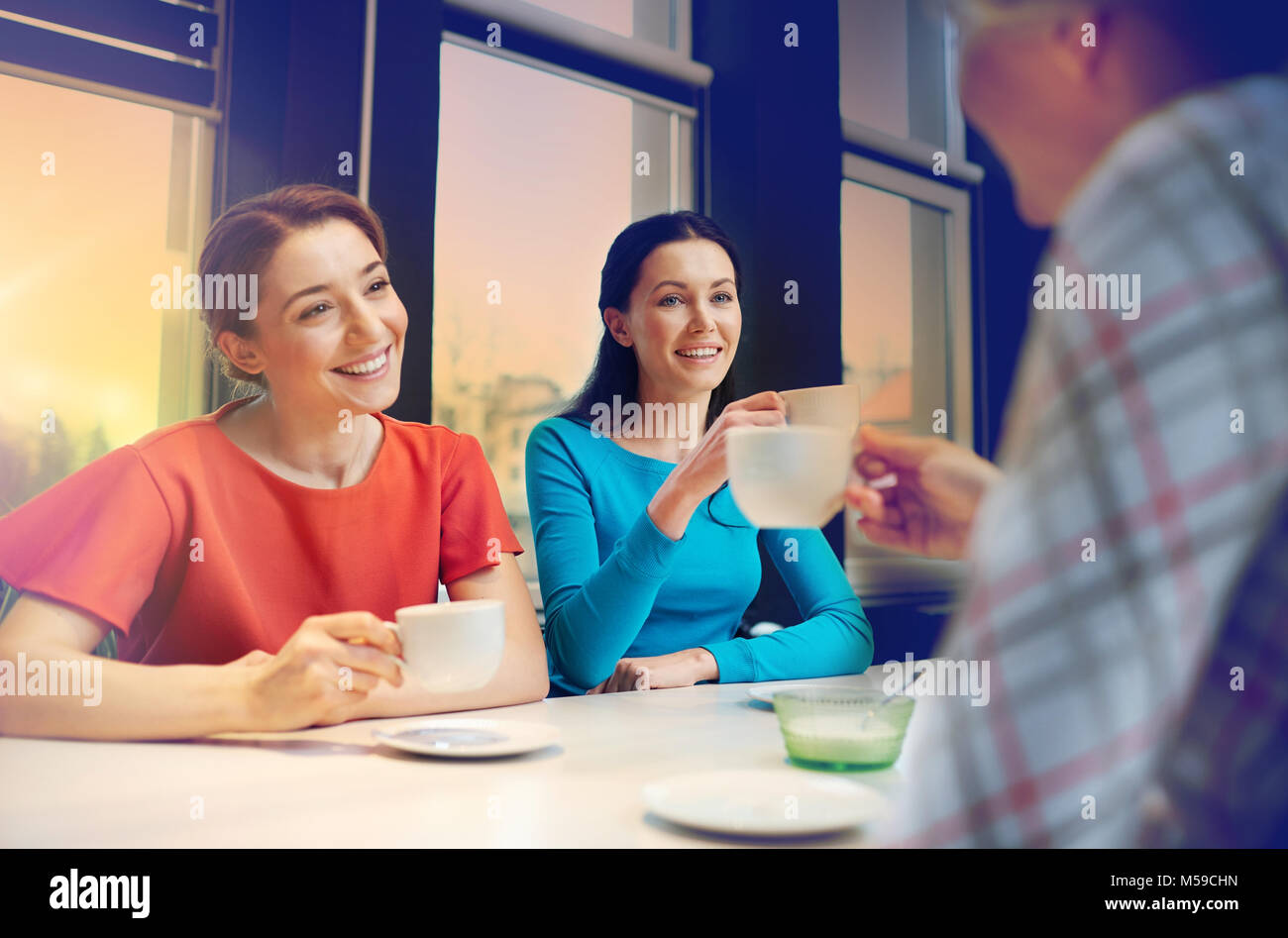 happy young women drinking tea or coffee at cafe Stock Photo - Alamy