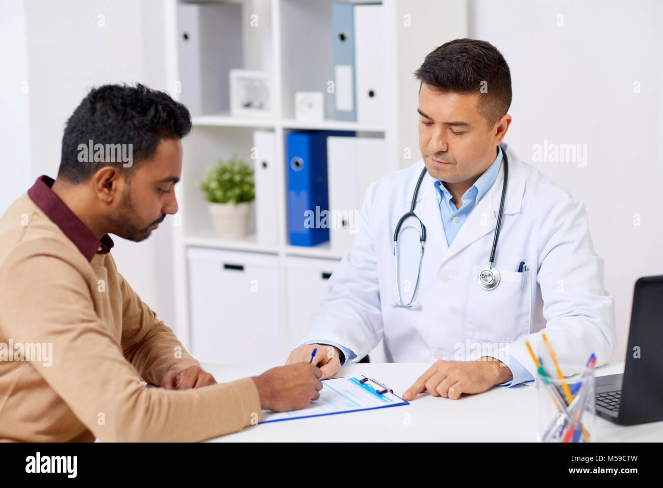 doctor and patient signing document at clinic Stock Photo - Alamy