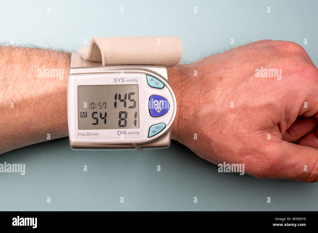 A mans arm with a blood pressure monitor attached with a reading of 145 ...