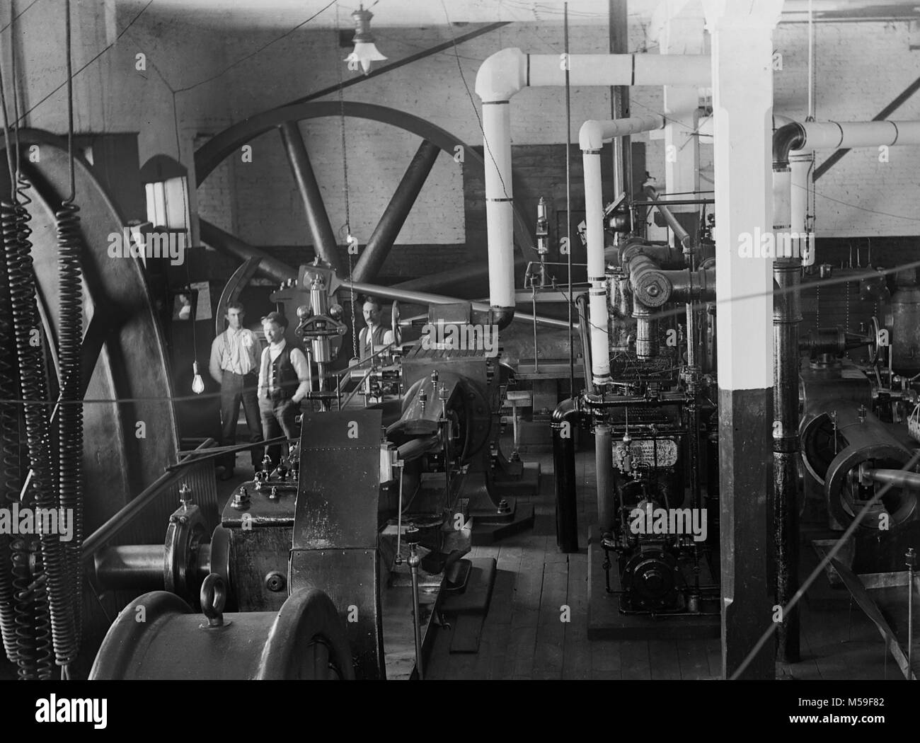 Workers stand in a turbine driven power plant, ca. 1900 Stock Photo - Alamy